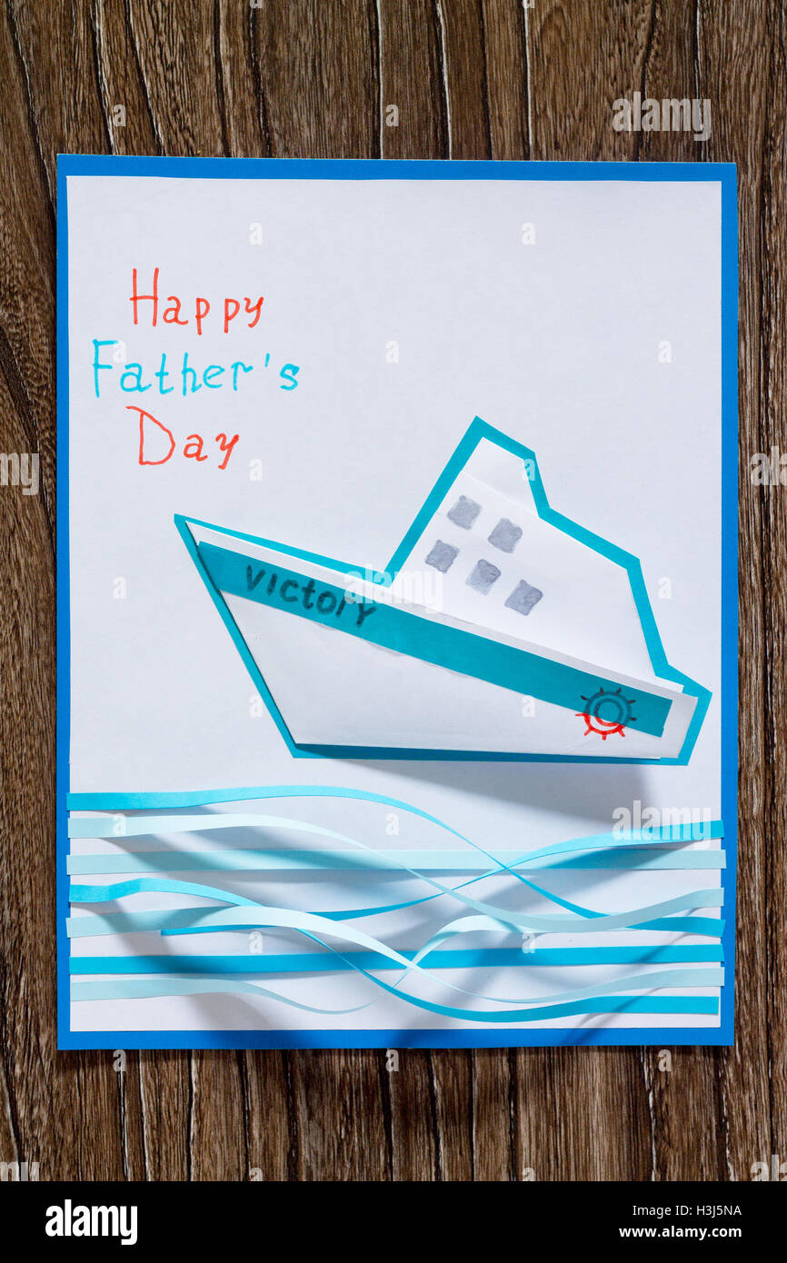 The child makes crafts out of paper boats. Greeting card for on Father ...