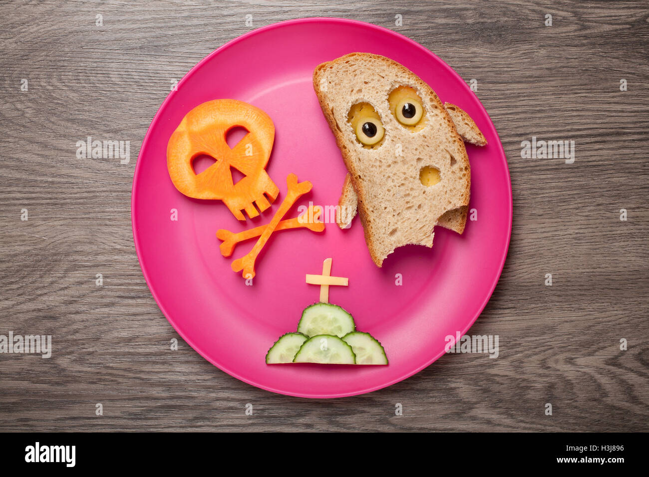 Halloween ghost and skull made of bread and carrot on plate and desk ...