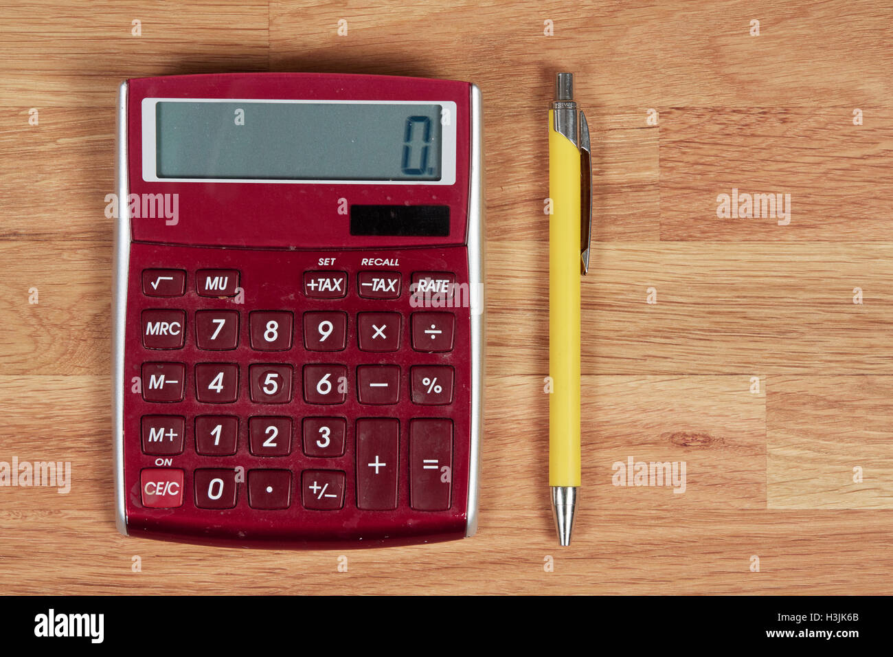 Red calculator and yellow pen on a wooden oak table Stock Photo - Alamy