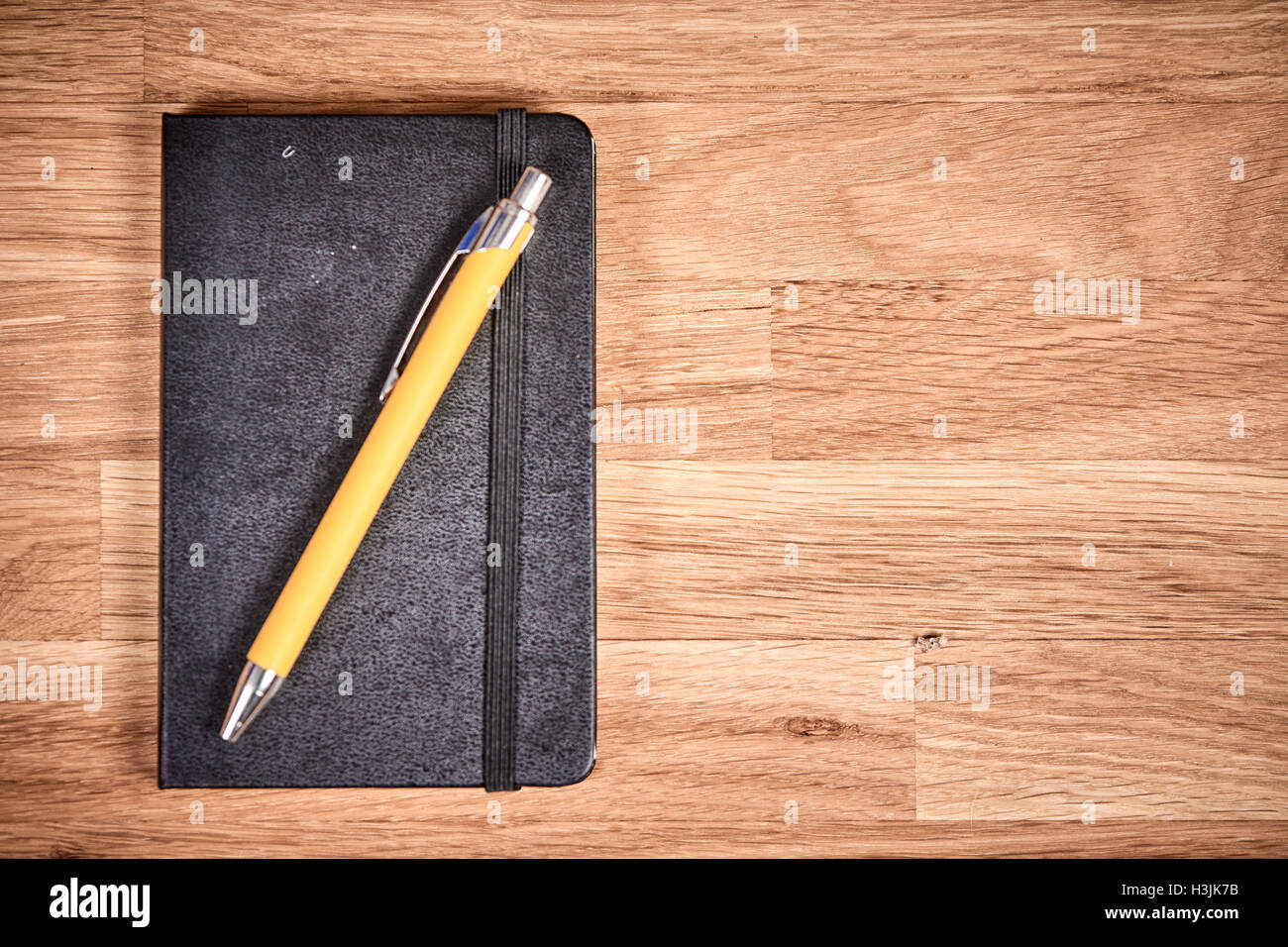 Closed notebook and yellow pen ballpoint on a brown wooden table Stock ...