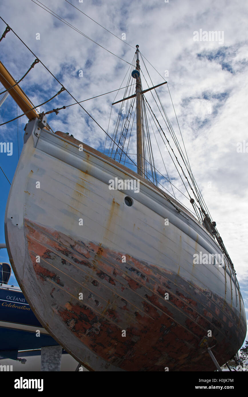 The hull of a wooden sailing boat undergoing work on the quayside at ...