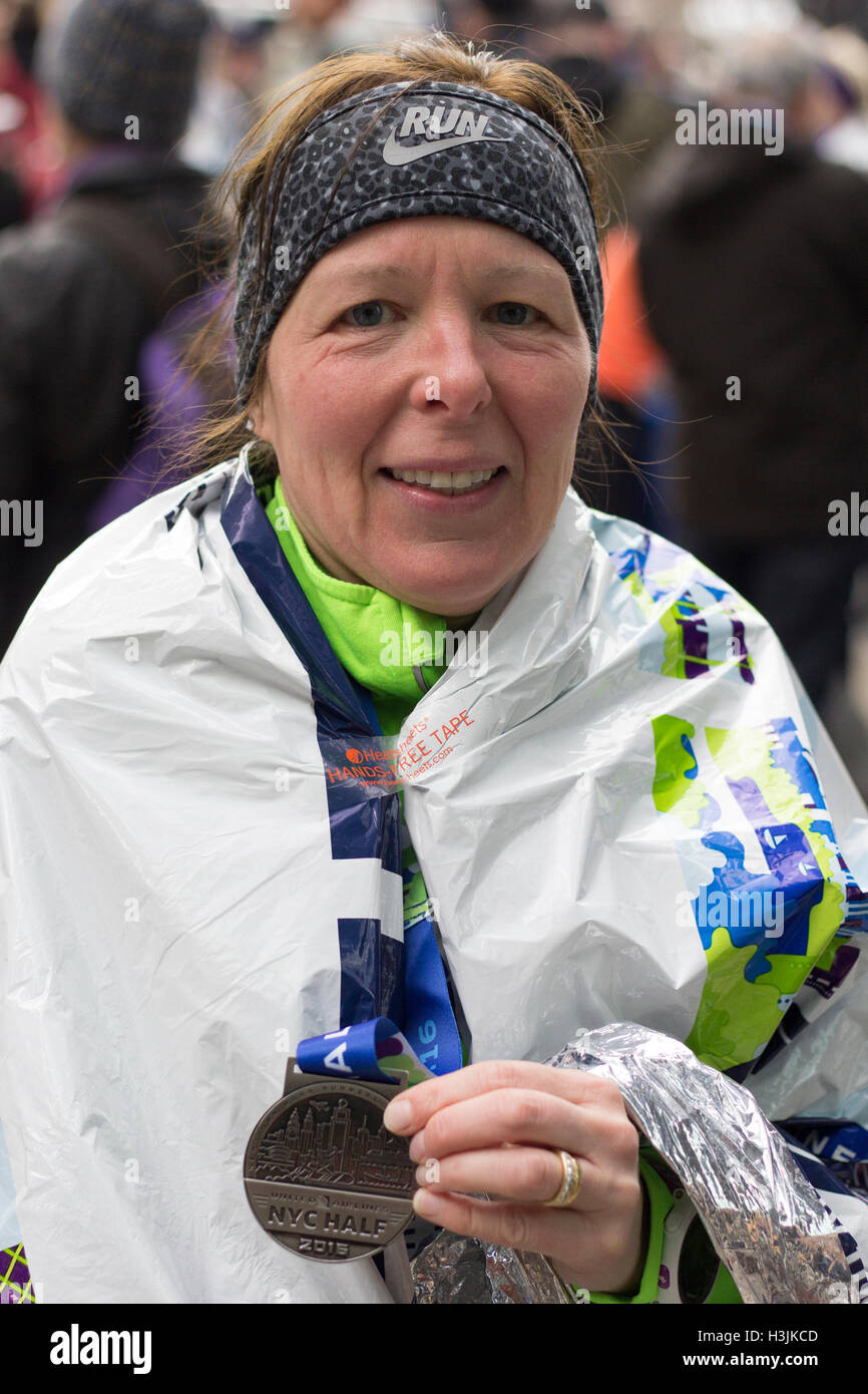 Female runner holds medal after completing NYC half marathon Stock ...