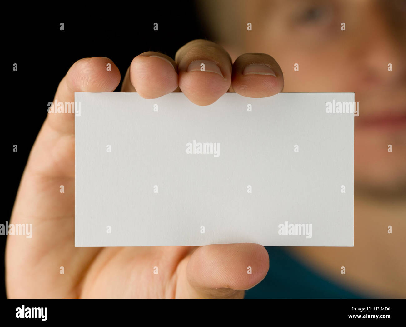 Man holding an blank white visit card template isolated on a black ...