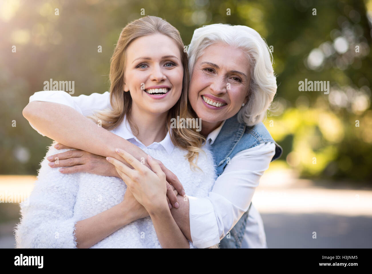 Two smiling friendly woman hugging in the park Stock Photo - Alamy