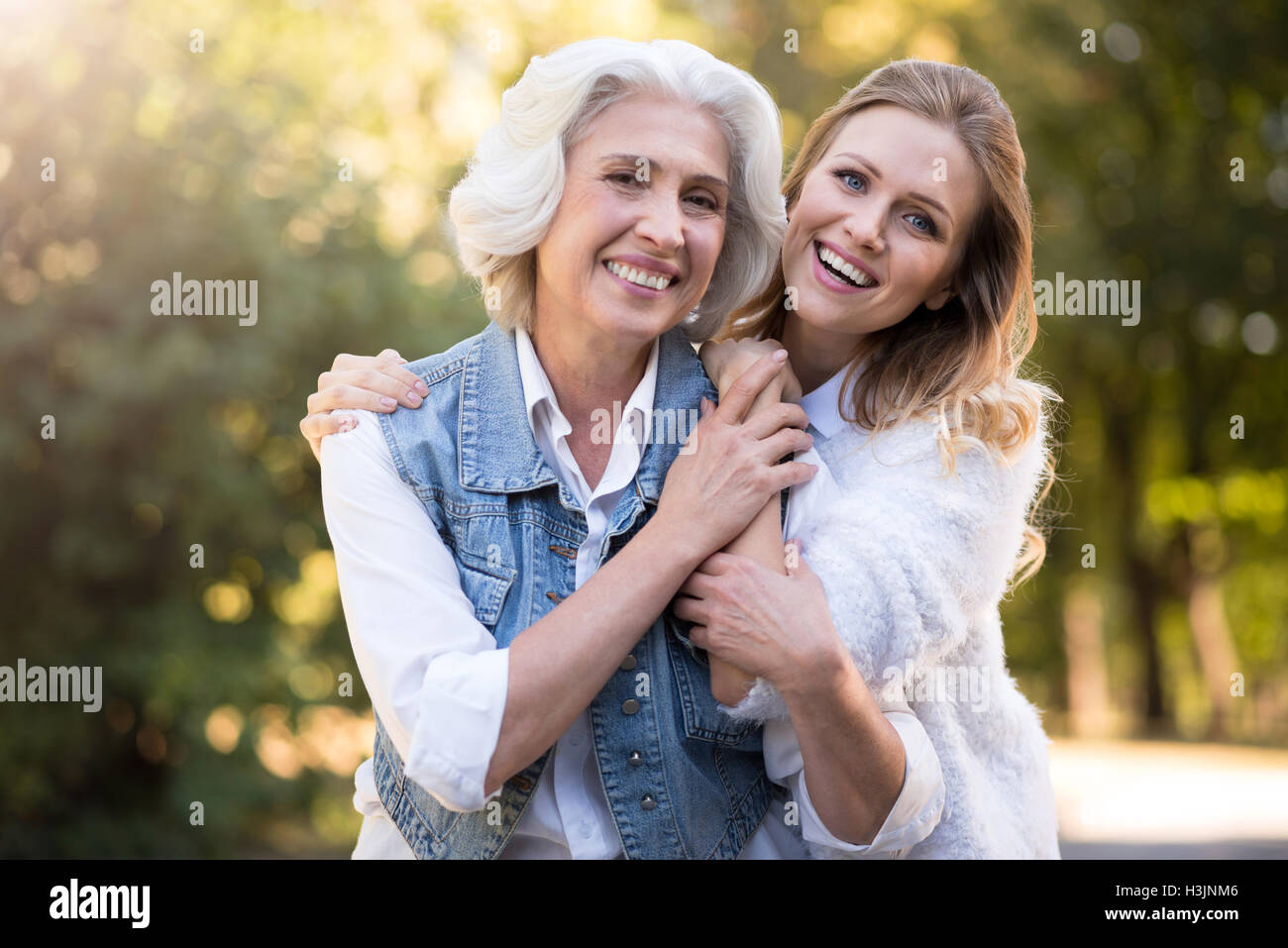 Two satisfied good looking women smiling and hugging Stock Photo - Alamy