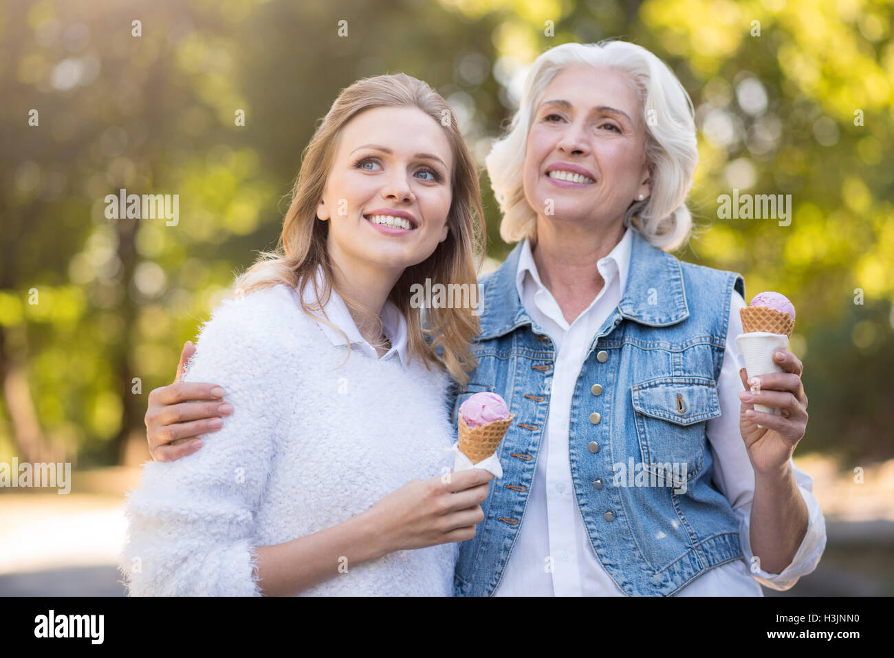 Two smiling charming women having a walk with ice cream Stock Photo - Alamy