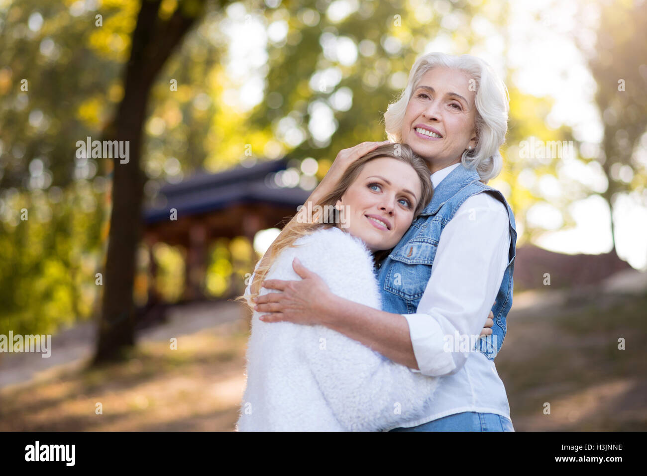 Two friendly beautiful women hugging each other in the park Stock Photo ...
