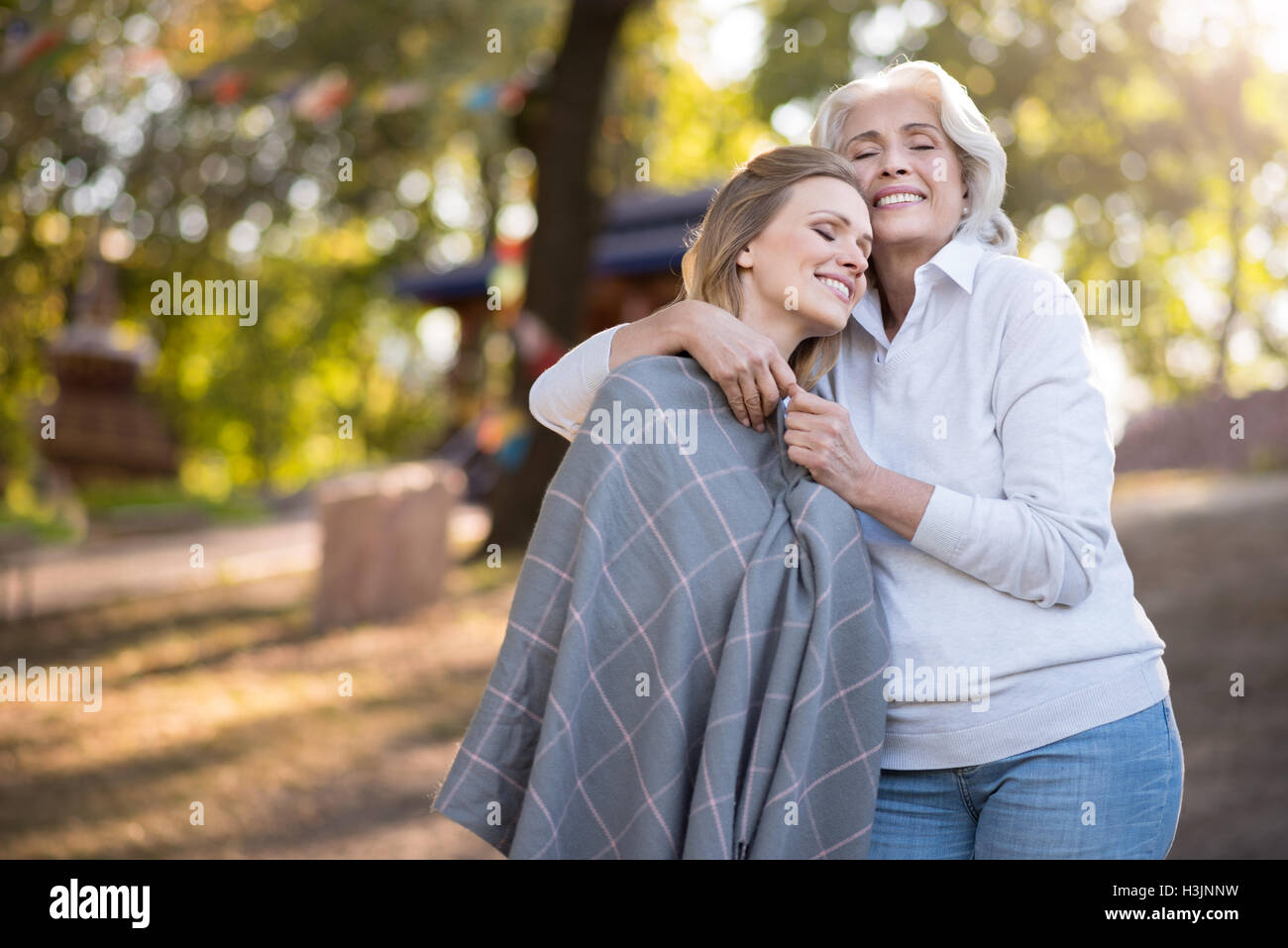 Two delighted women hugging and smiling in the park Stock Photo - Alamy