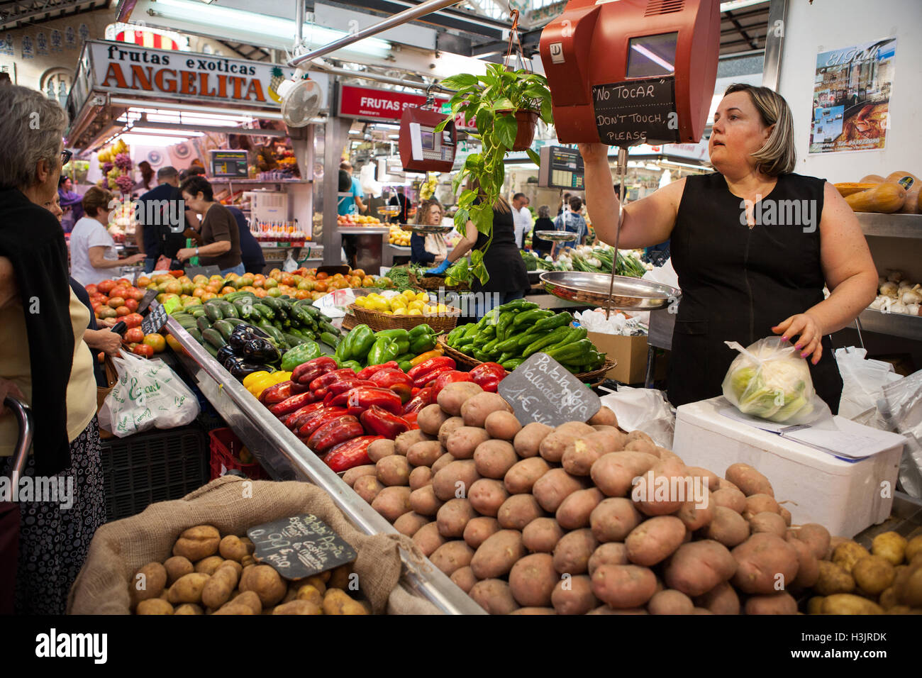 A grocer weighs produce on a set of scales at a fruit and vegetable ...