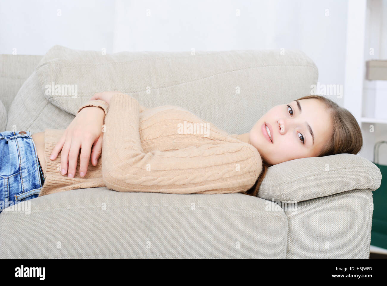 smiling young woman lying on couch Stock Photo - Alamy