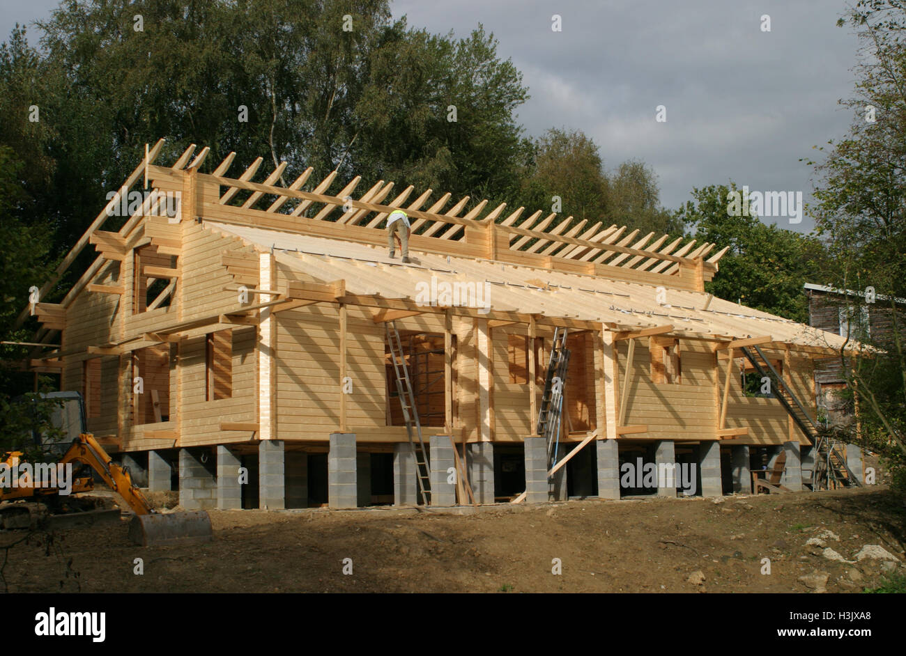 A worker uses a gas-powered nail gun to fasten roofing boards on a ...