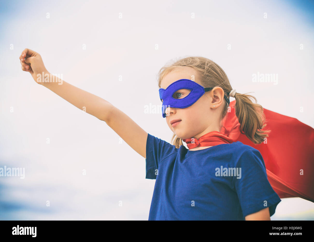 Superhero kid against blue sky background Stock Photo - Alamy
