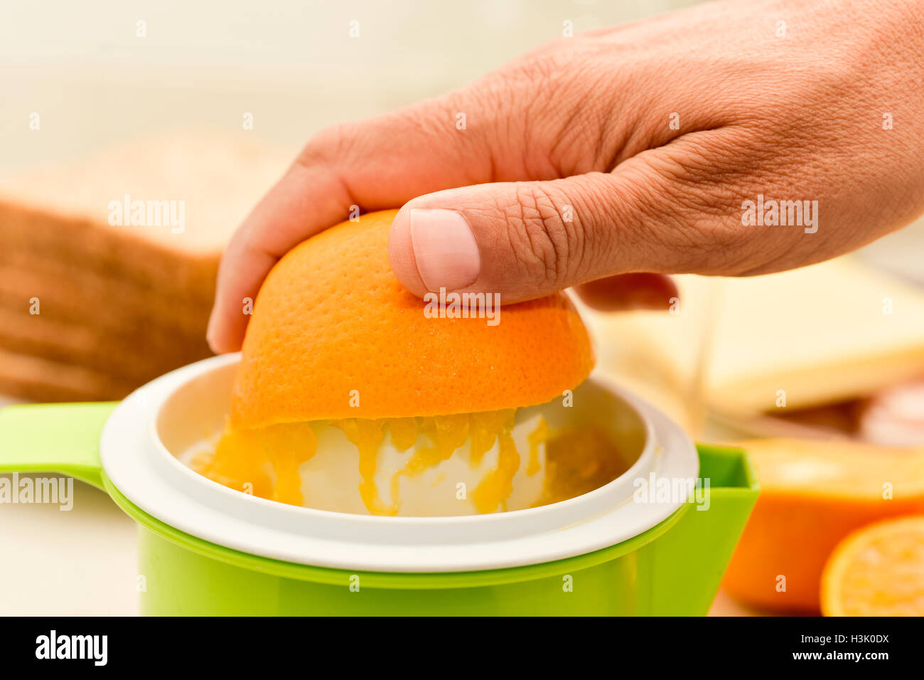 closeup of a young caucasian man squeezing oranges with a plastic ...