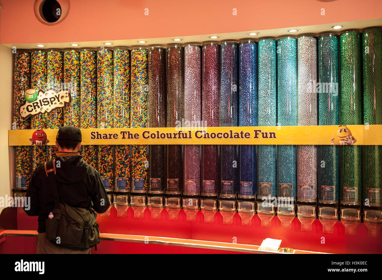 Man in front of colorful M&M crispy candy assortments inside the ...