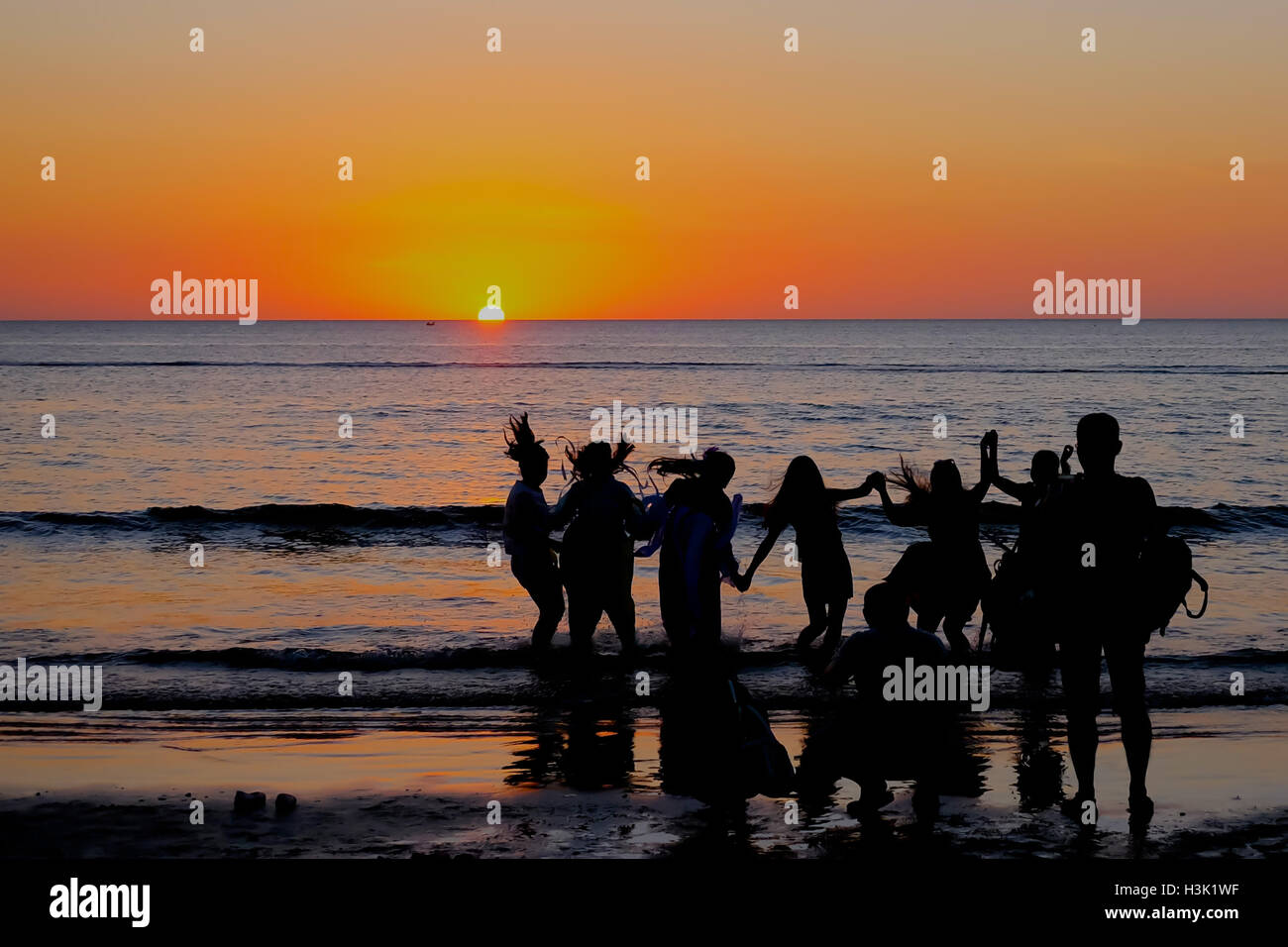 A group of people are enjoying the beautiful sunset view at the beach ...