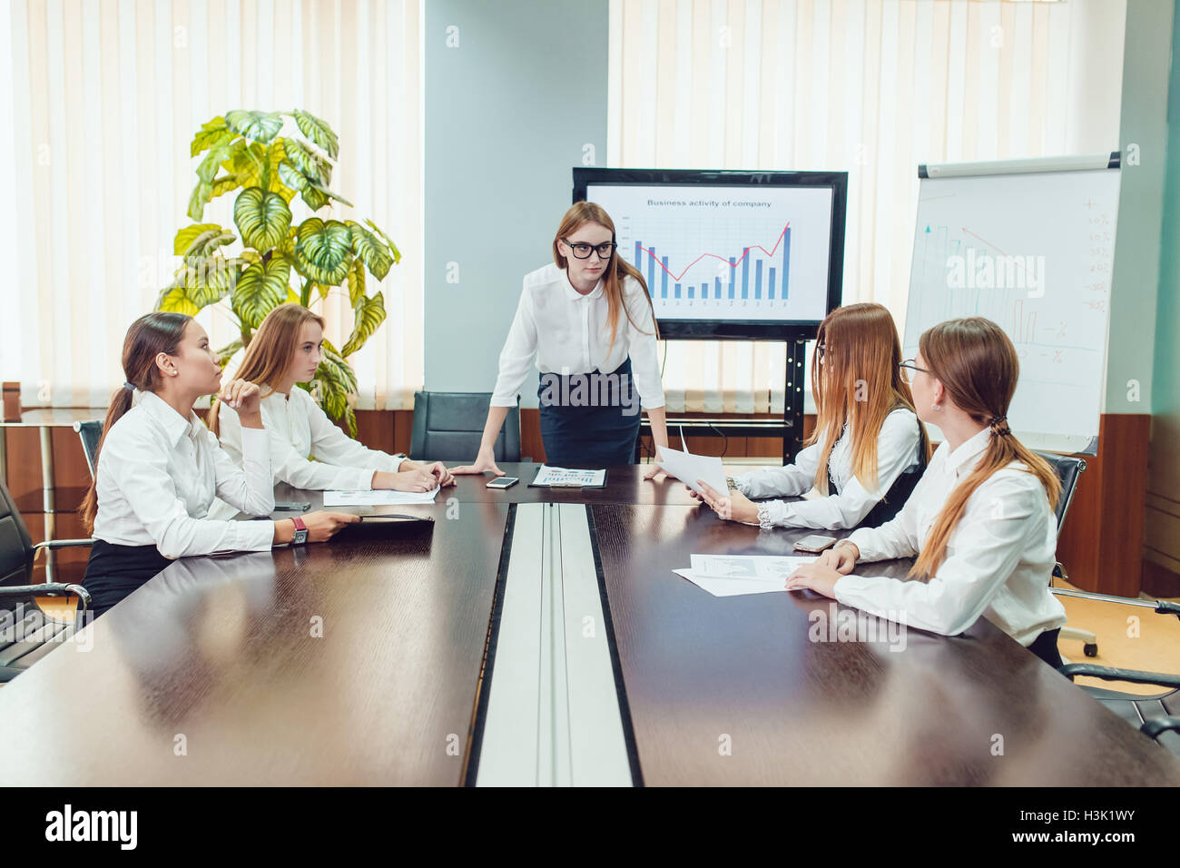 Female boss appeals to workers sitting at the table Stock Photo - Alamy