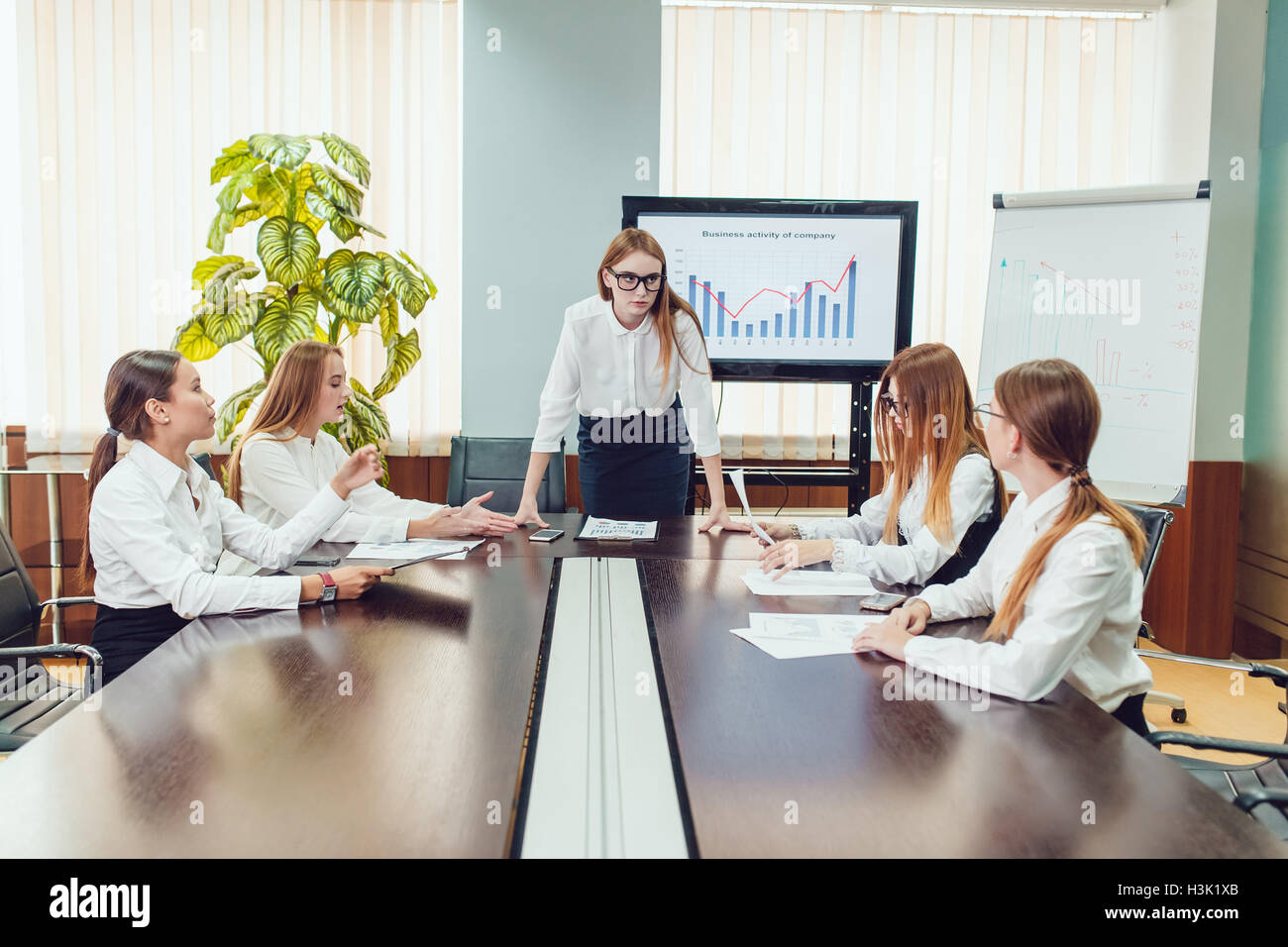 Female boss appeals to workers sitting at the table Stock Photo - Alamy