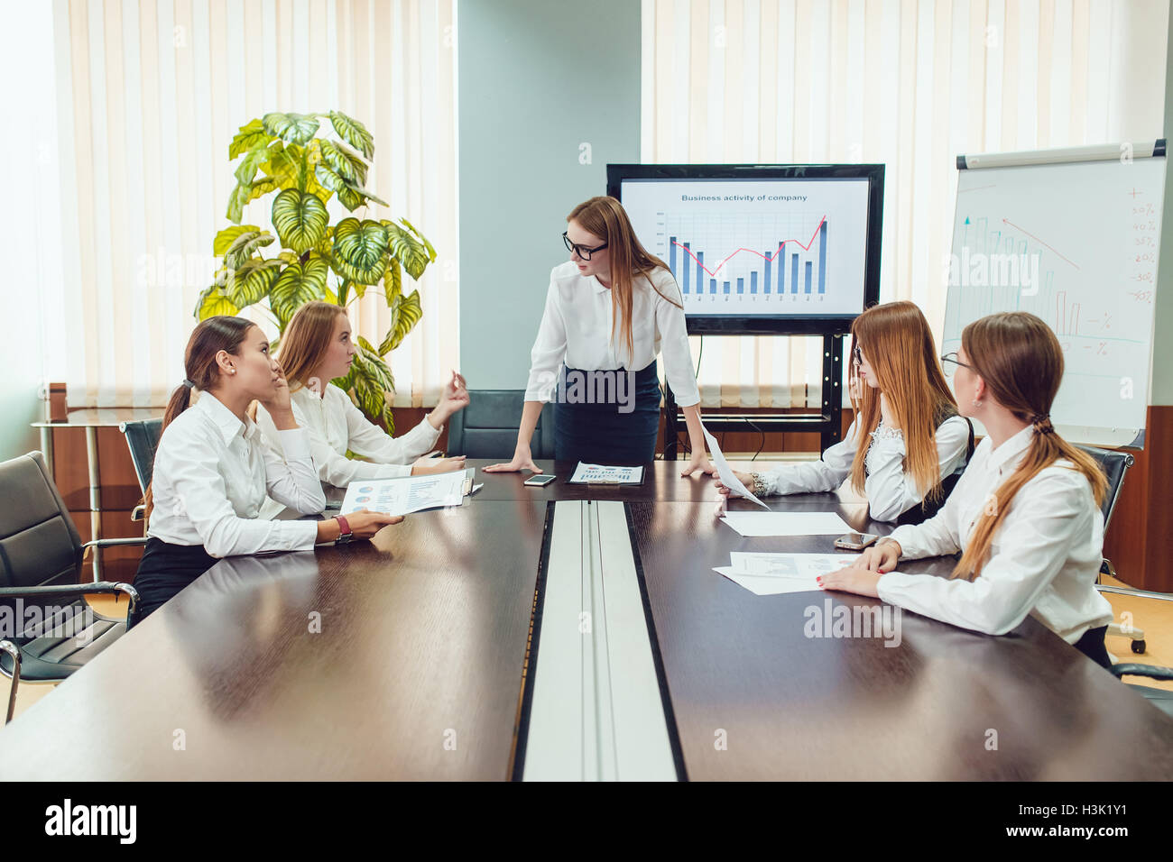 Female boss appeals to workers sitting at the table Stock Photo - Alamy