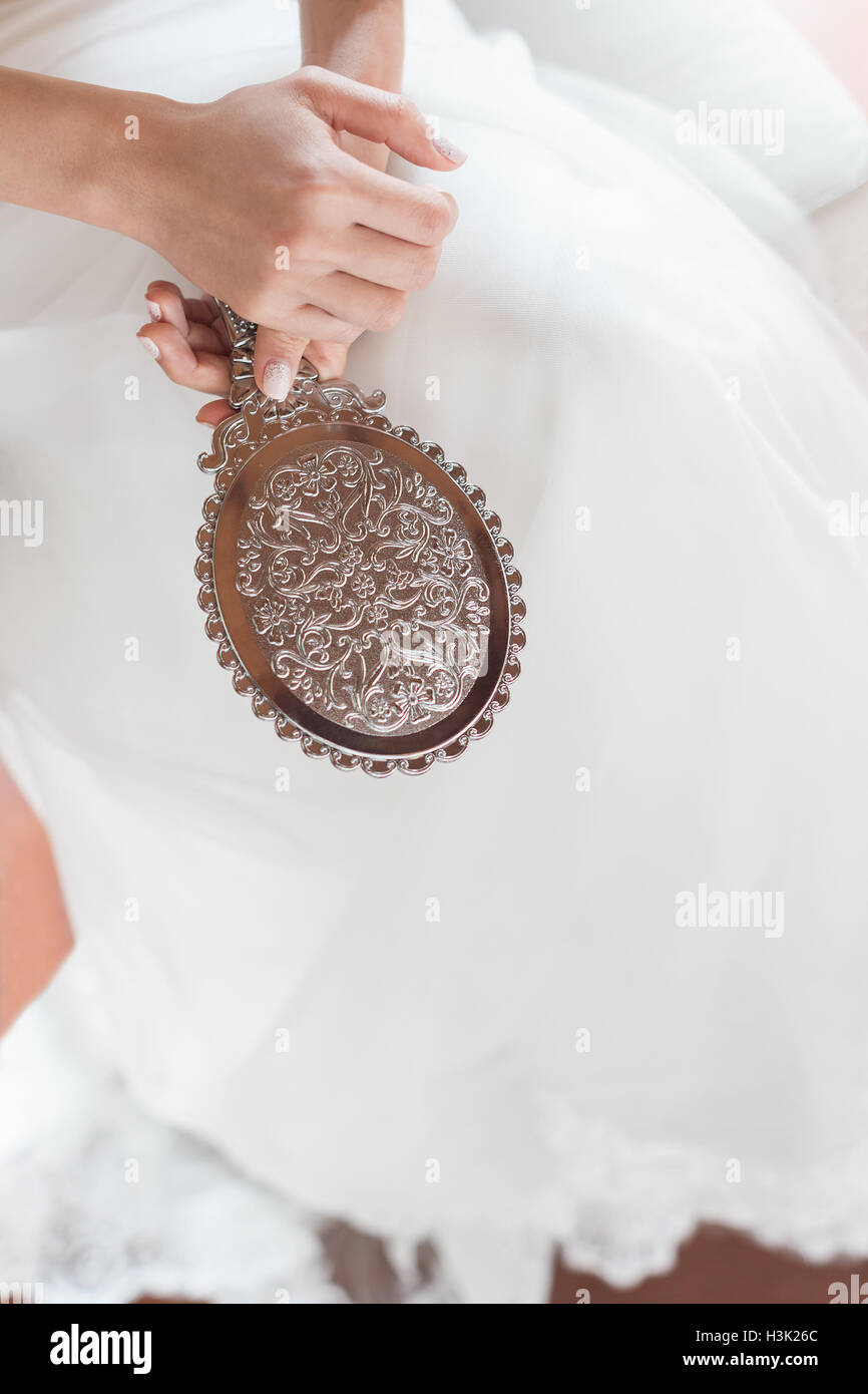 Bride join hands with antique pattern mirror on her white wedding dress ...