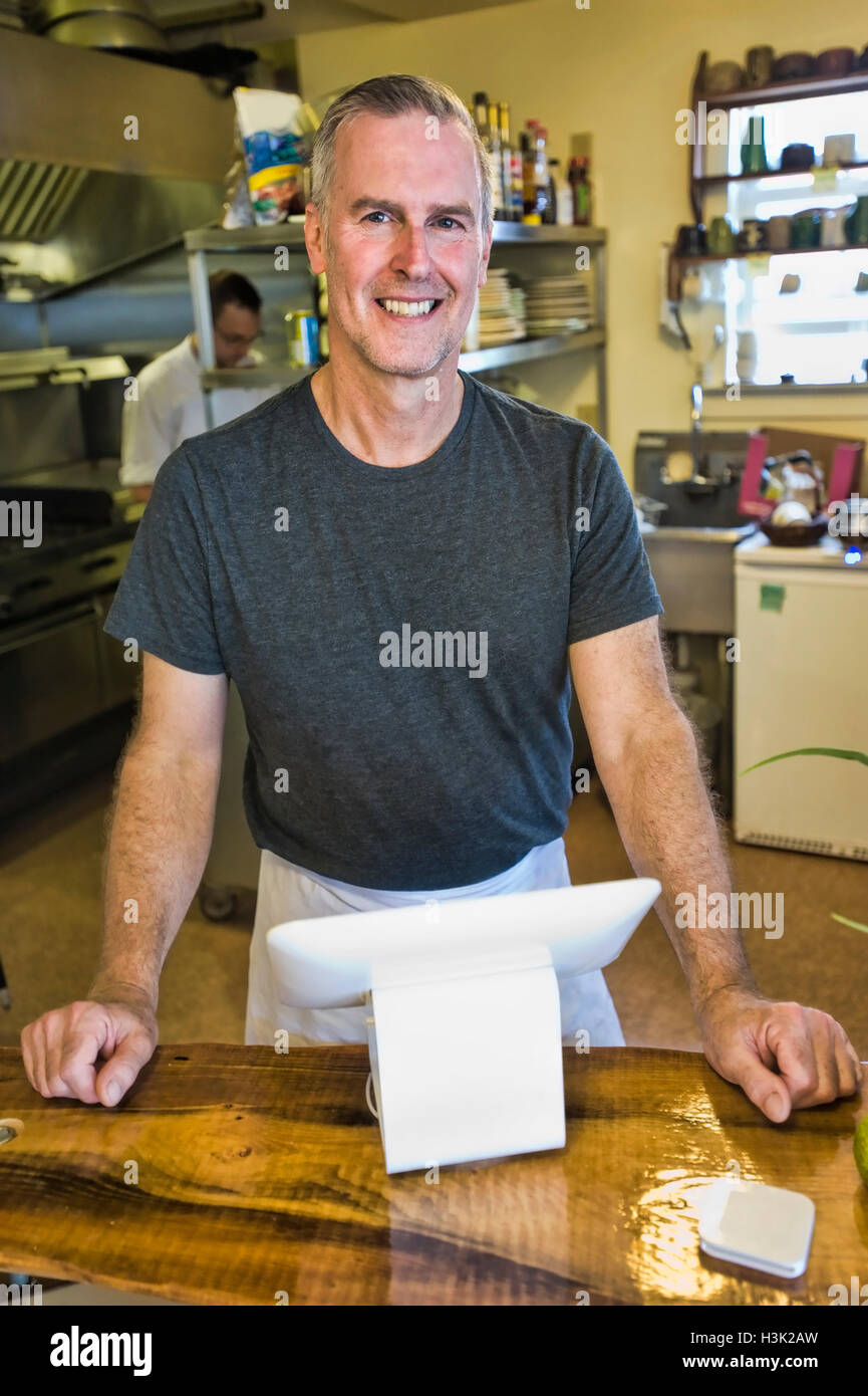 Cafe owner smiling behind service counter Stock Photo - Alamy
