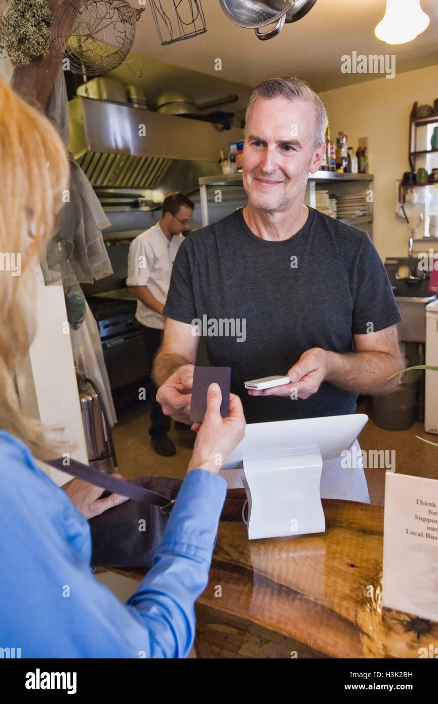 Cafe owner serving customer in restaurant Stock Photo - Alamy
