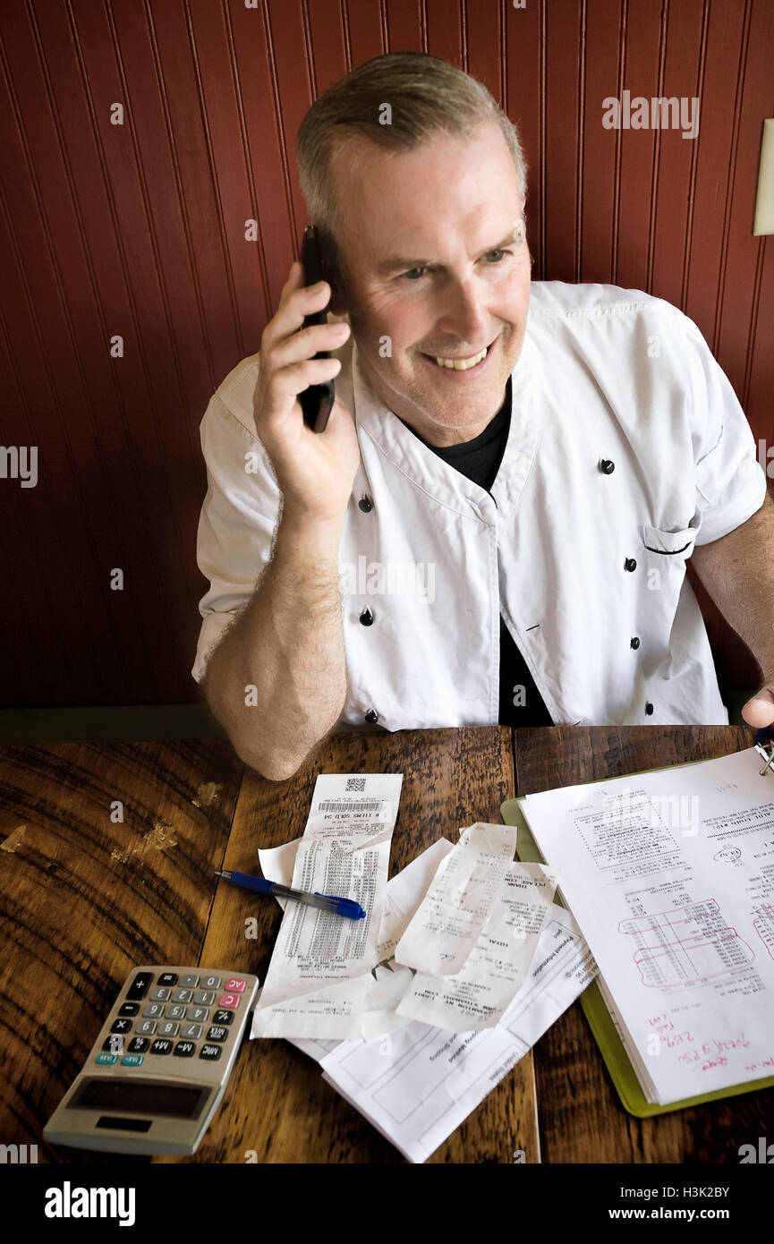 Chef working on accounts, using cellphone Stock Photo - Alamy