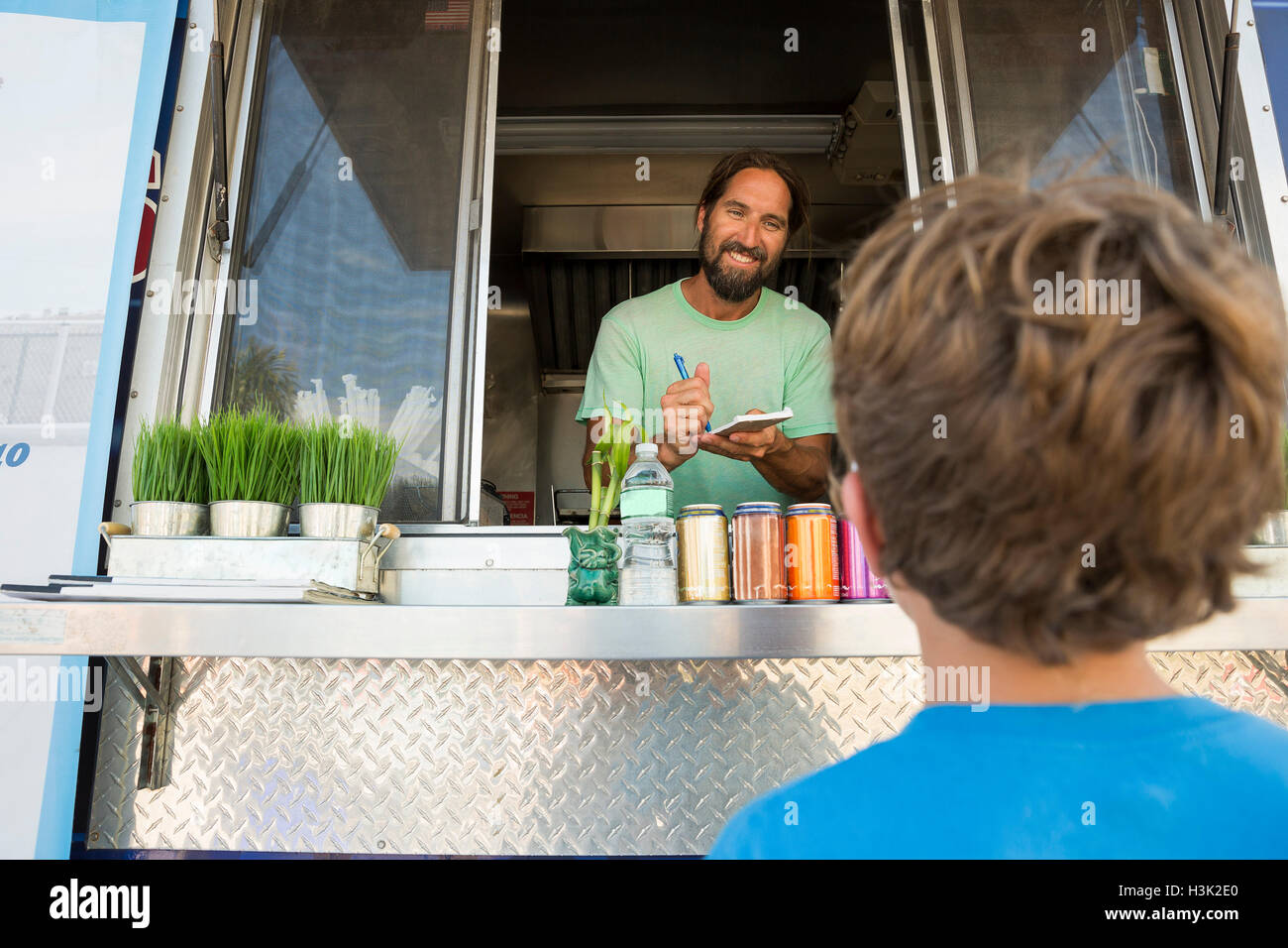 Man in fast food trailer serving young boy through hatch Stock Photo ...