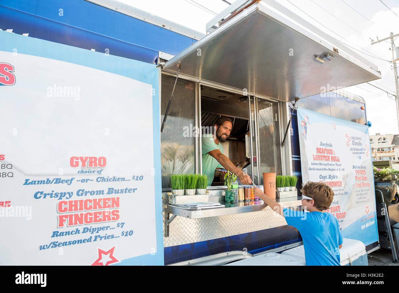 Man in fast food trailer serving young boy through hatch Stock Photo ...