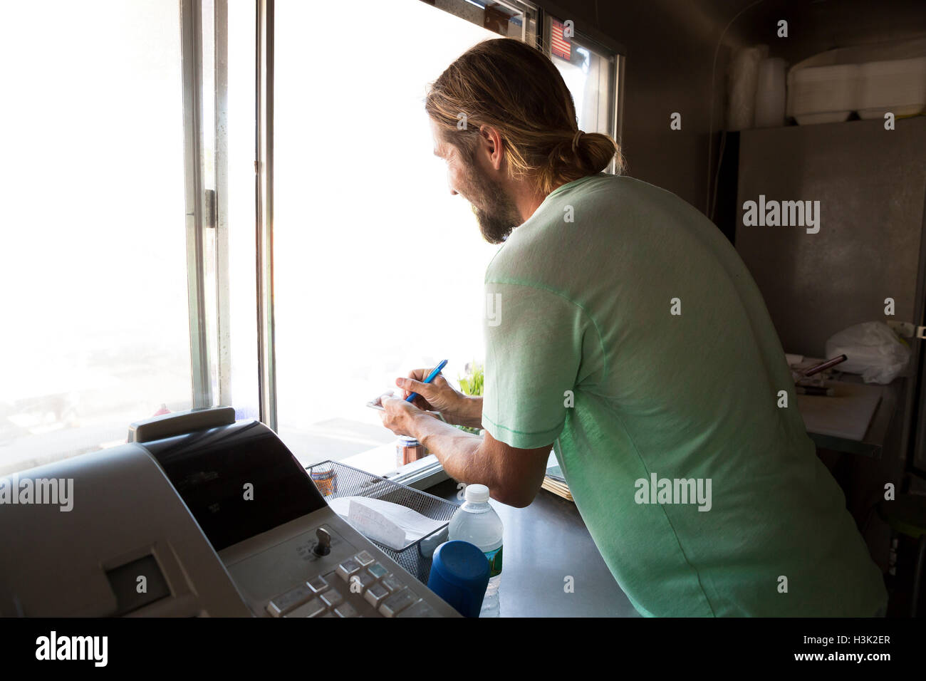 Man in fast food trailer, leaning through hatch, taking customer's ...
