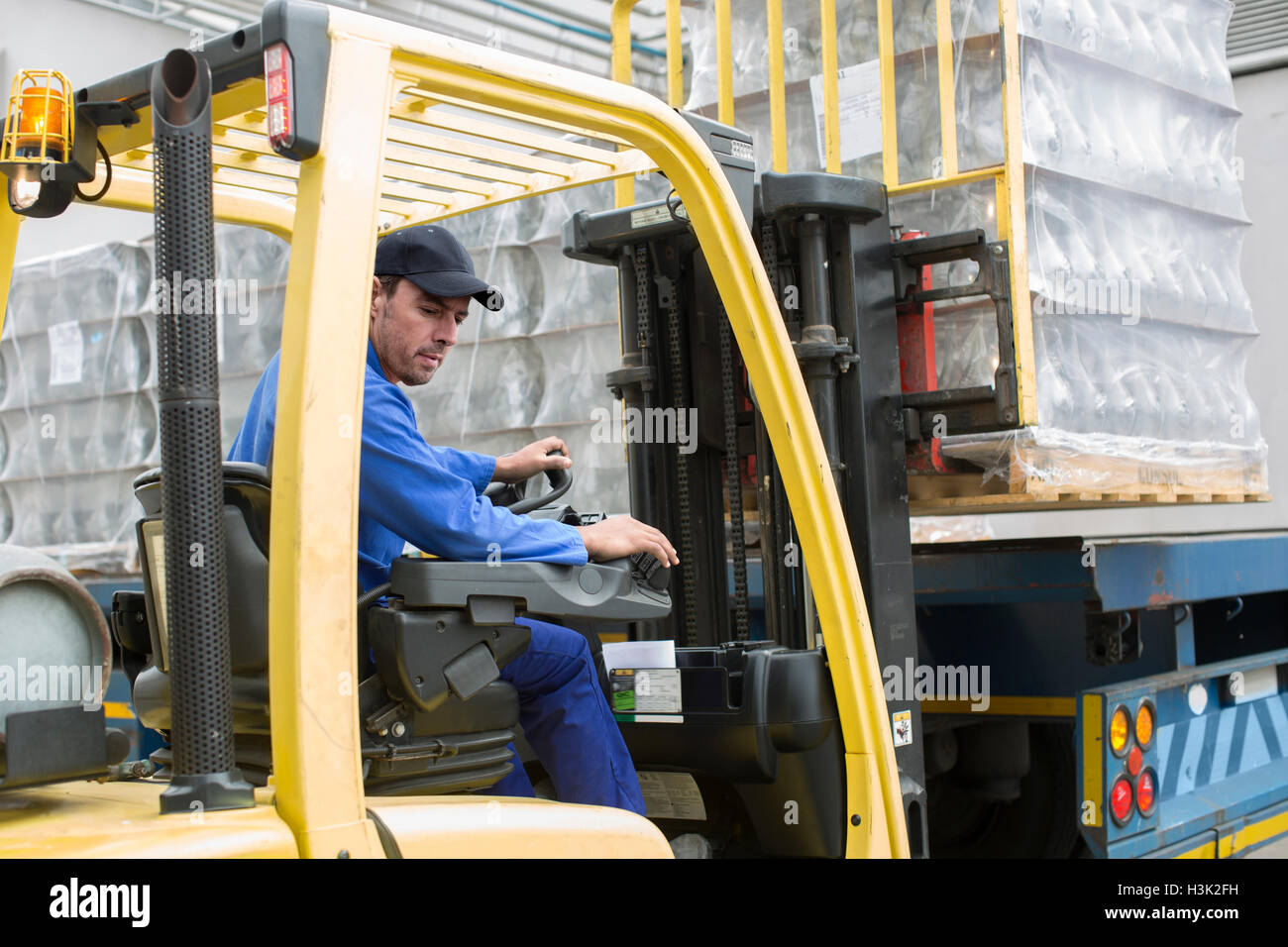 Forklift driver loading pallet onto truck at packaging factory Stock ...