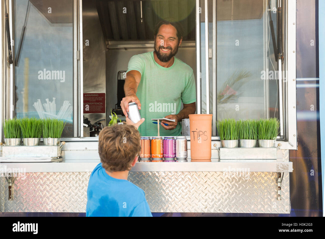 Man in fast food trailer passing drink to boy through hatch Stock Photo ...