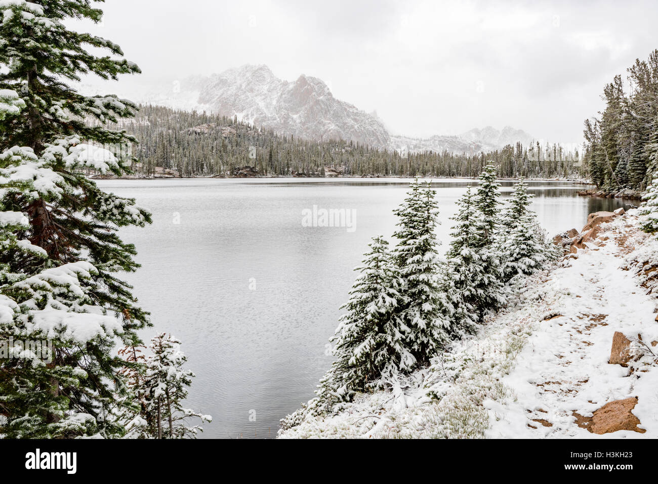 Snow covered foot path leads around a mountain lake Stock Photo - Alamy