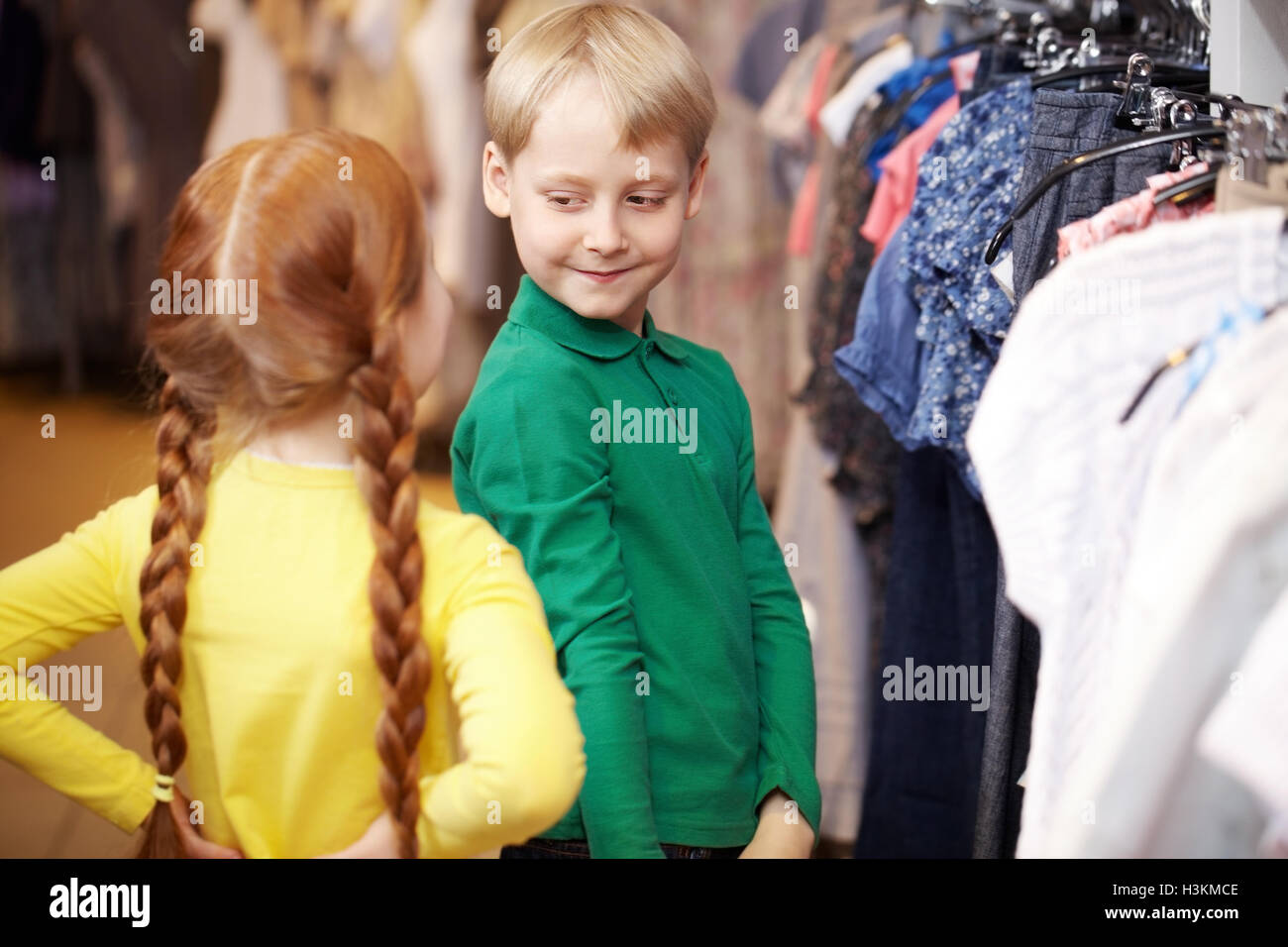 A little boy and girl standing at racks with clothes in shop Stock ...