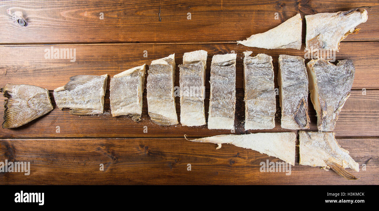 Traditional cut of salted cod on a wooden board Stock Photo - Alamy