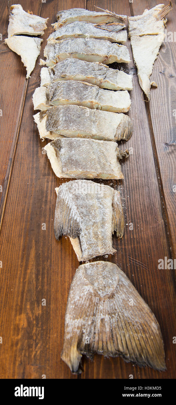 Traditional cut of salted cod on a wooden board Stock Photo - Alamy