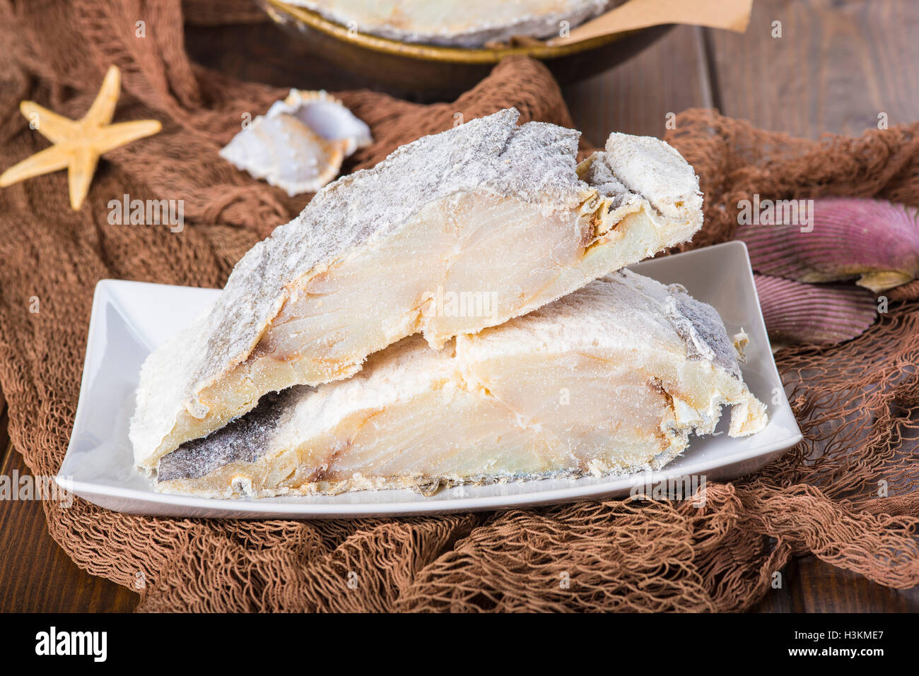Uncooked salted preserved cod cut in portions on fishing nets Stock ...