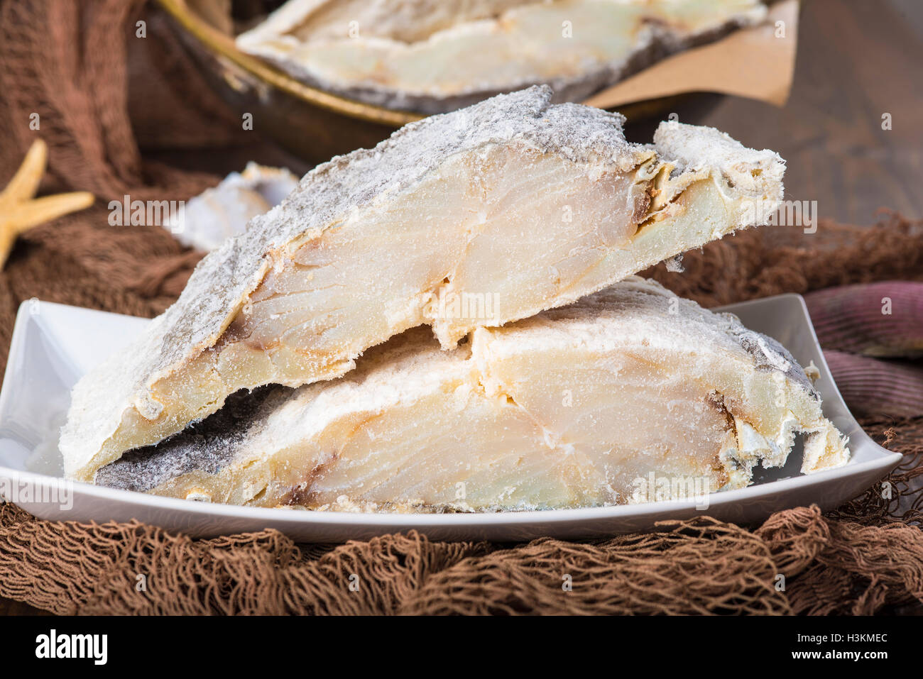 Uncooked salted preserved cod cut in portions on fishing nets Stock ...