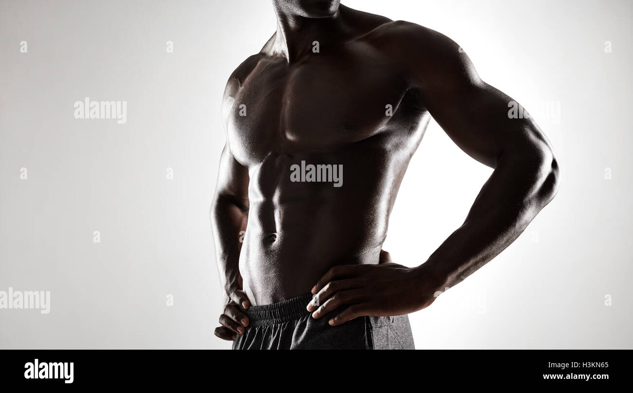 Cropped shot of african man with muscular body standing against grey ...