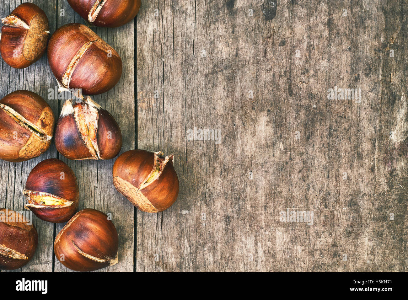 Roasted sweet chestnuts on grey rustic wooden table. Top view with ...
