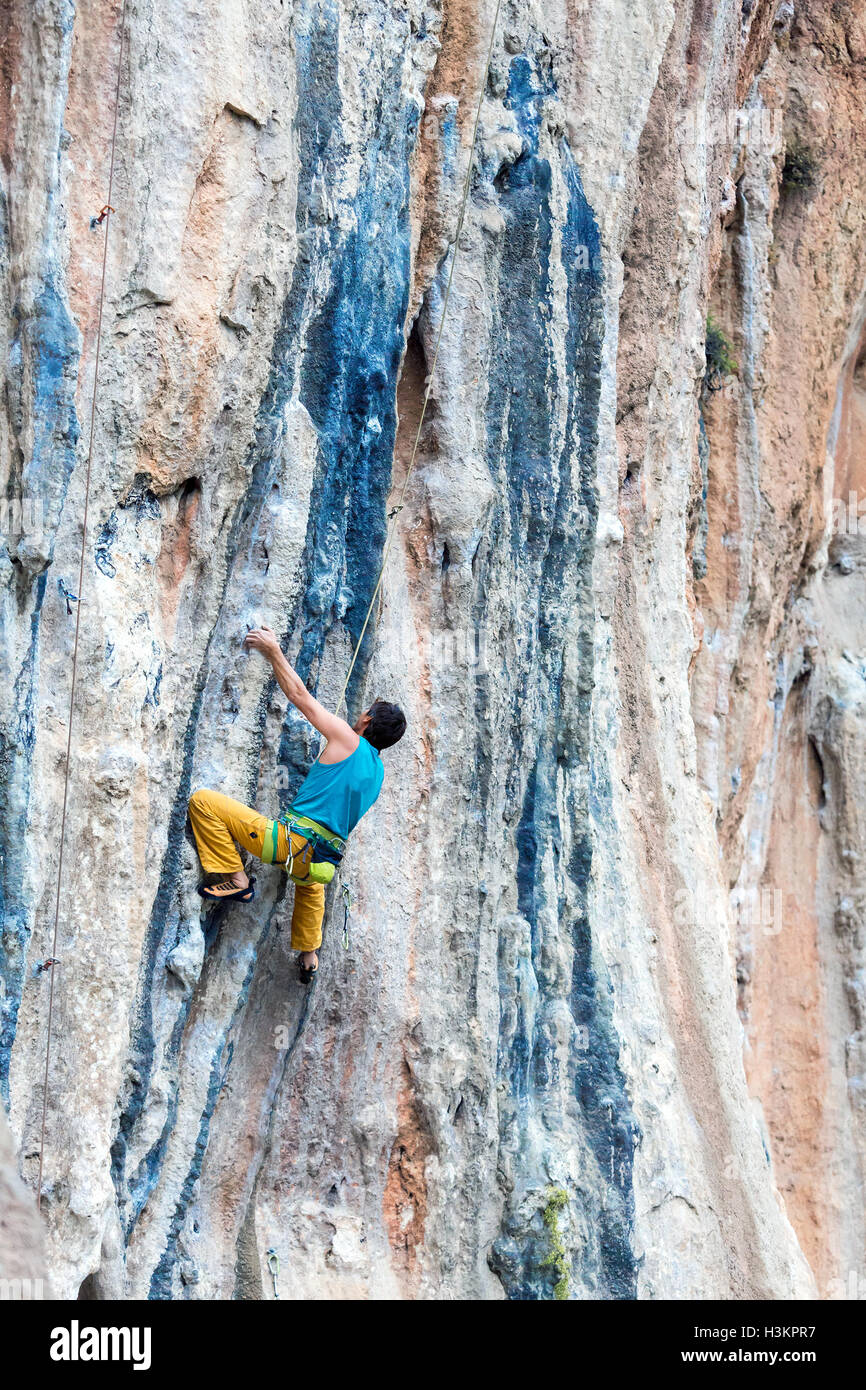 Mature Rock Climber ascending steep colorful rocky Wall Lead Climbing ...