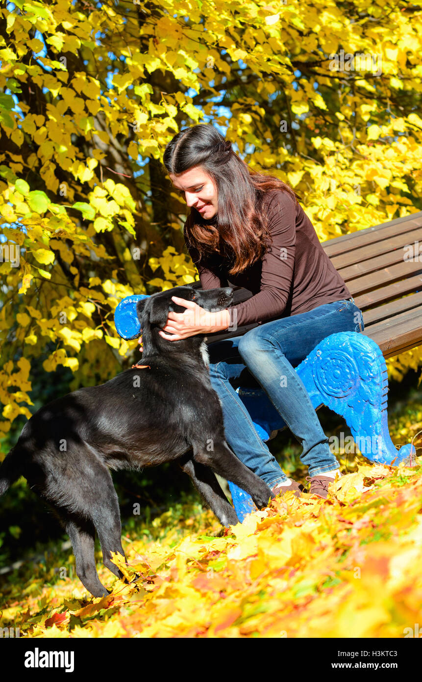 Portrait of a beautiful young woman looking to her dog while resting in ...