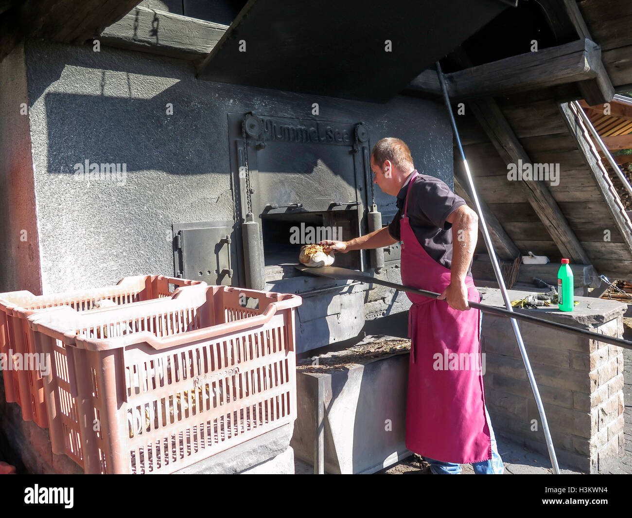 Baker is baking bread in a traditional ancient wood burning brick oven ...