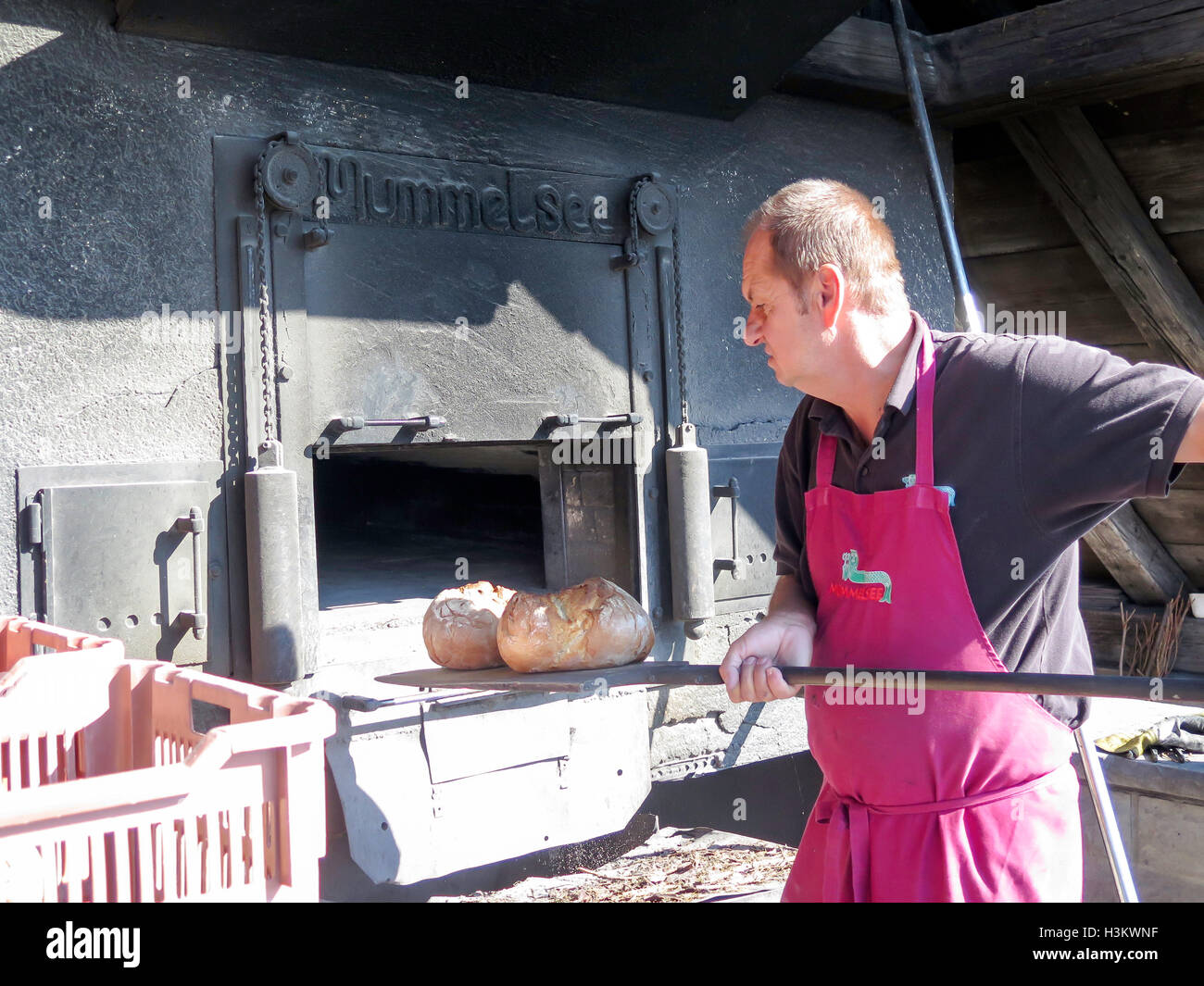 Baker is baking bread in a traditional ancient wood burning brick oven ...