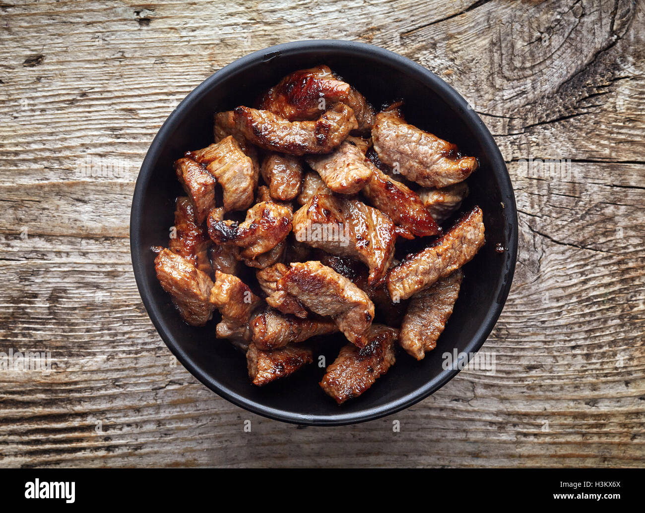 Bowl of grilled beef chunks on wooden table, top view Stock Photo - Alamy