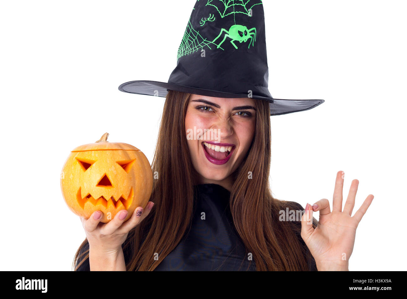 Woman in costume of witch holding a pumpkin and showing OKAY Stock ...