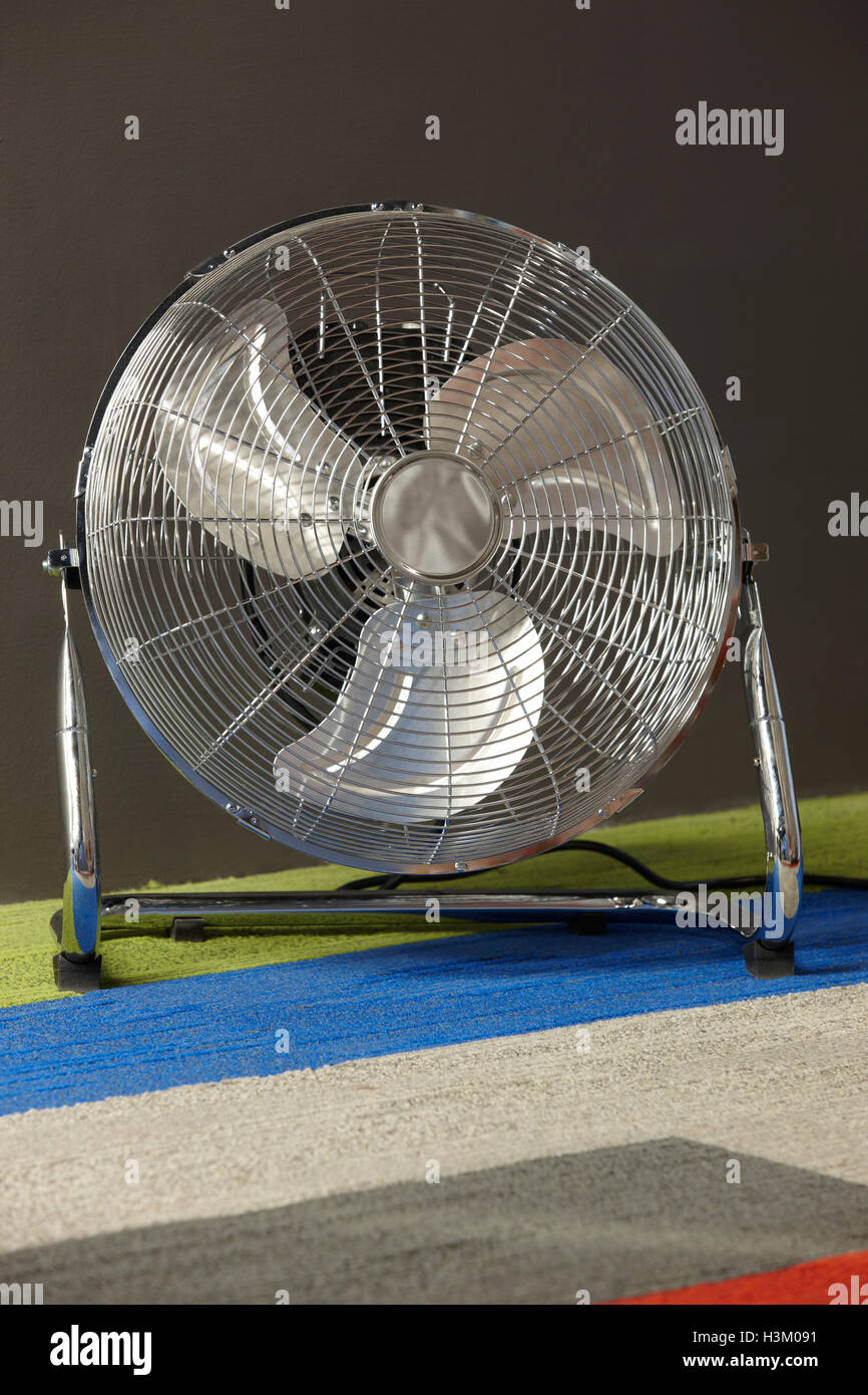 Chrome electric fan over a multicolored carpet. Vertical Stock Photo ...