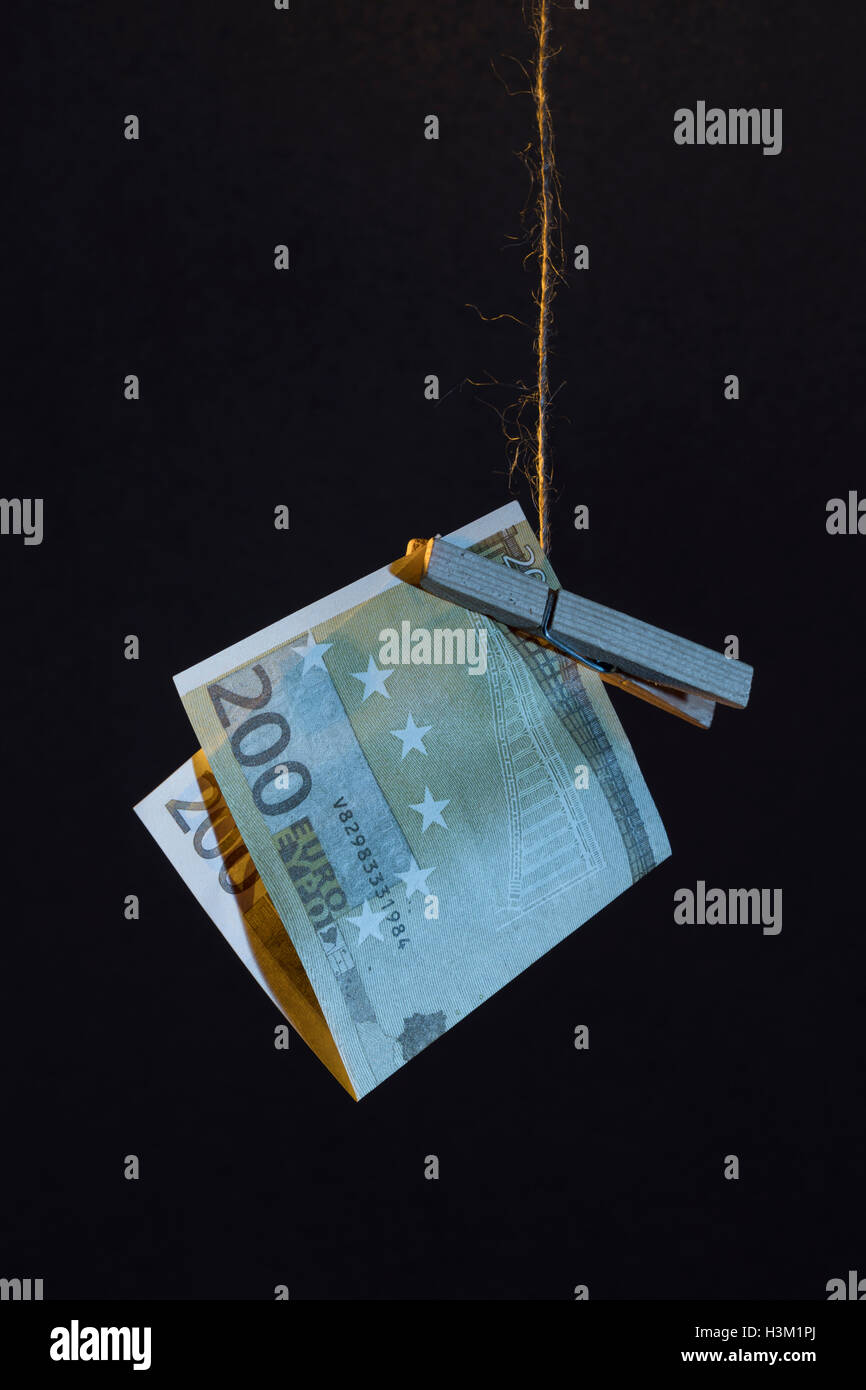 20 Euro note hanging on frayed string against a dark background ...