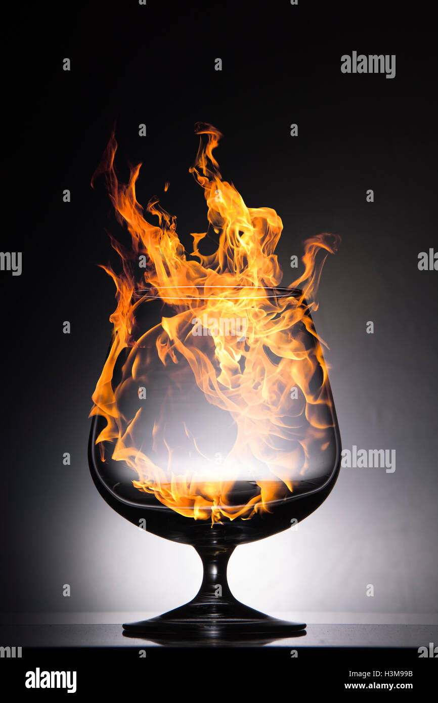 Composite image of burning glass with raging flames on a black ...