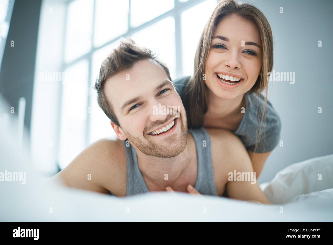 Cheerful couple lying in bed in the morning Stock Photo - Alamy