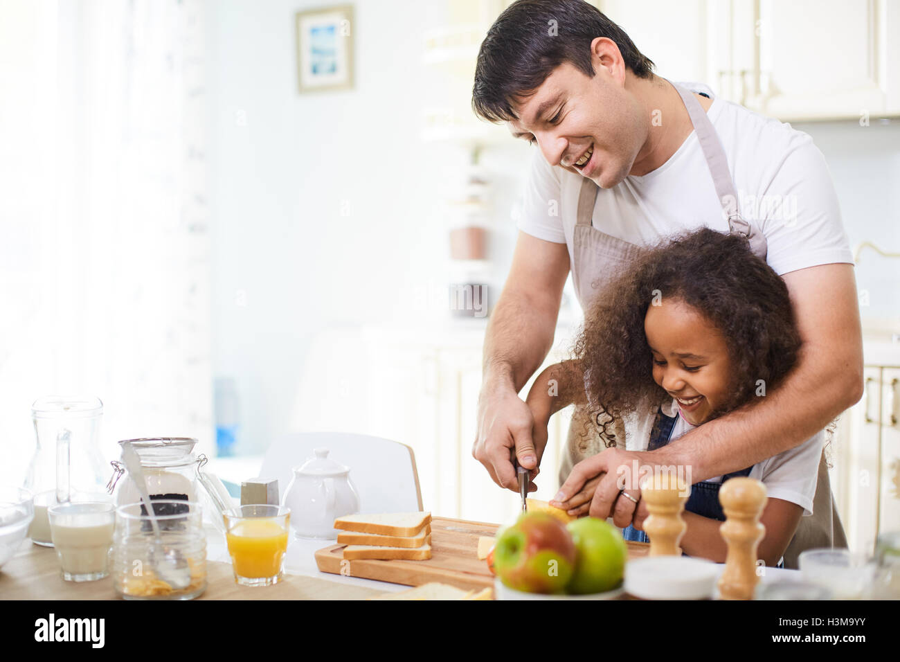 Young father showing his daughter how to cut bread Stock Photo - Alamy